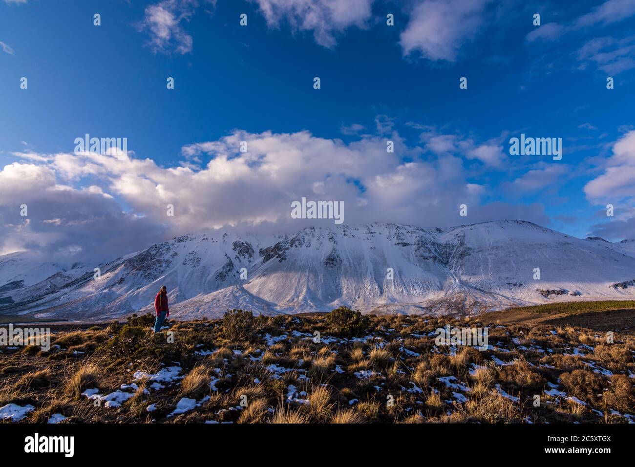 Scene view of a woman hiking against snow covered Andes mountains in ...