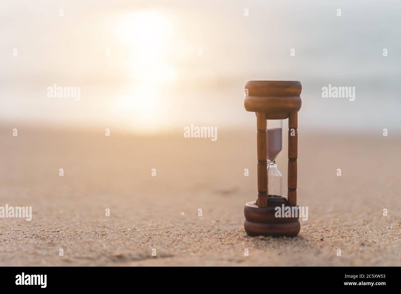 Small hourglass show time is flowing on sand beach texture background ...