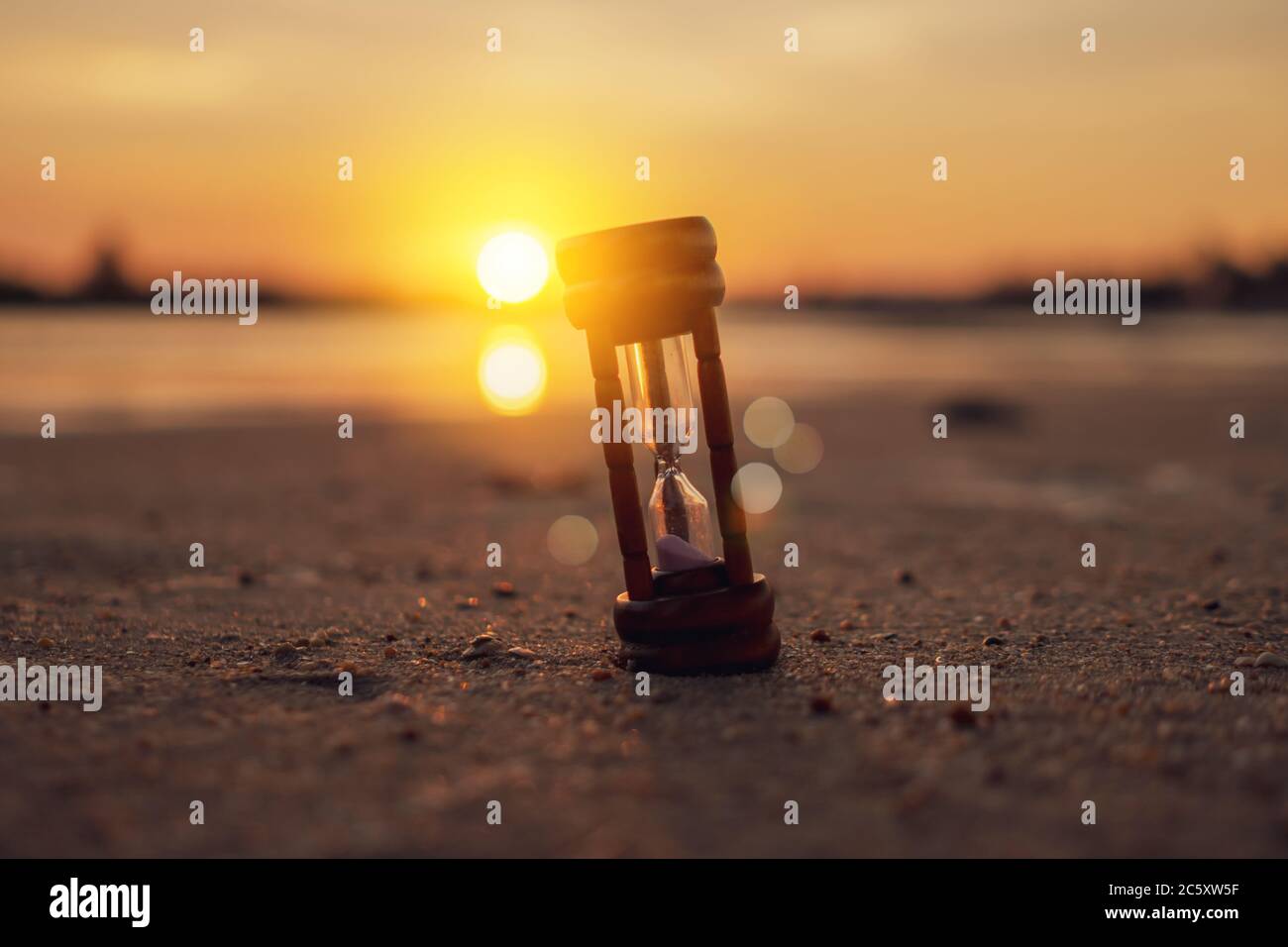Small hourglass show time is flowing on sand beach texture background ...