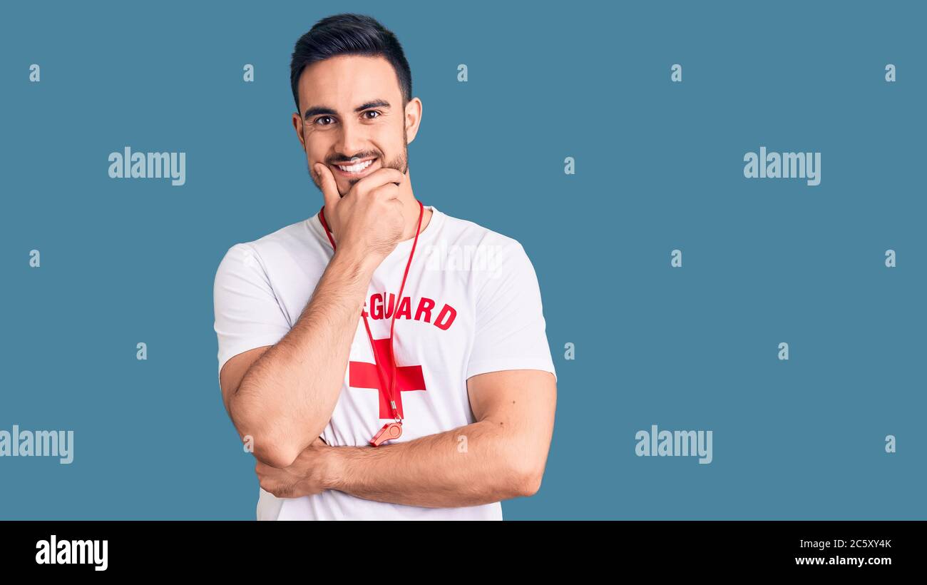 Young handsome man wearing lifeguard uniform looking confident at the ...