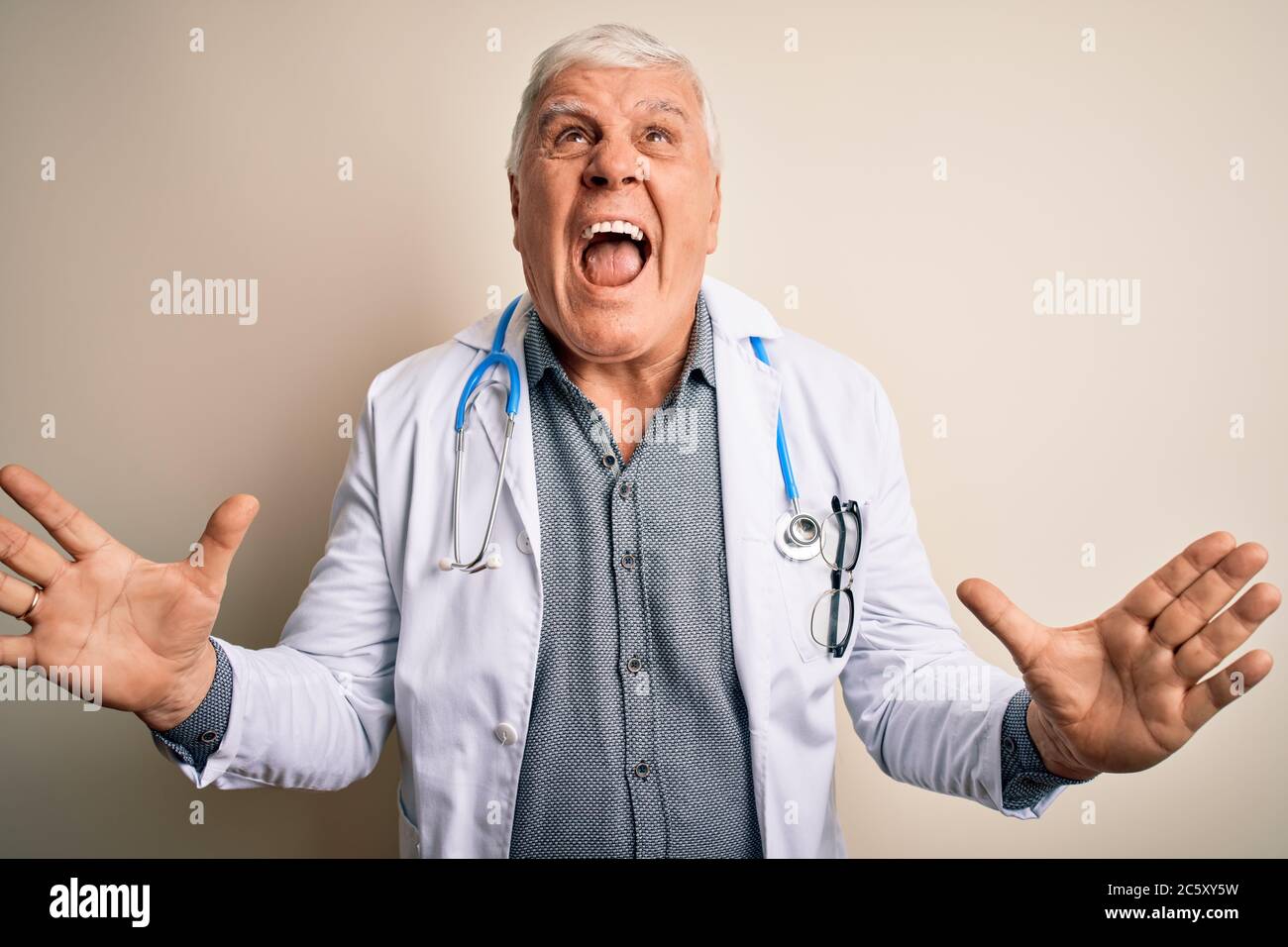 Senior handsome hoary doctor man wearing coat and stethoscope over ...