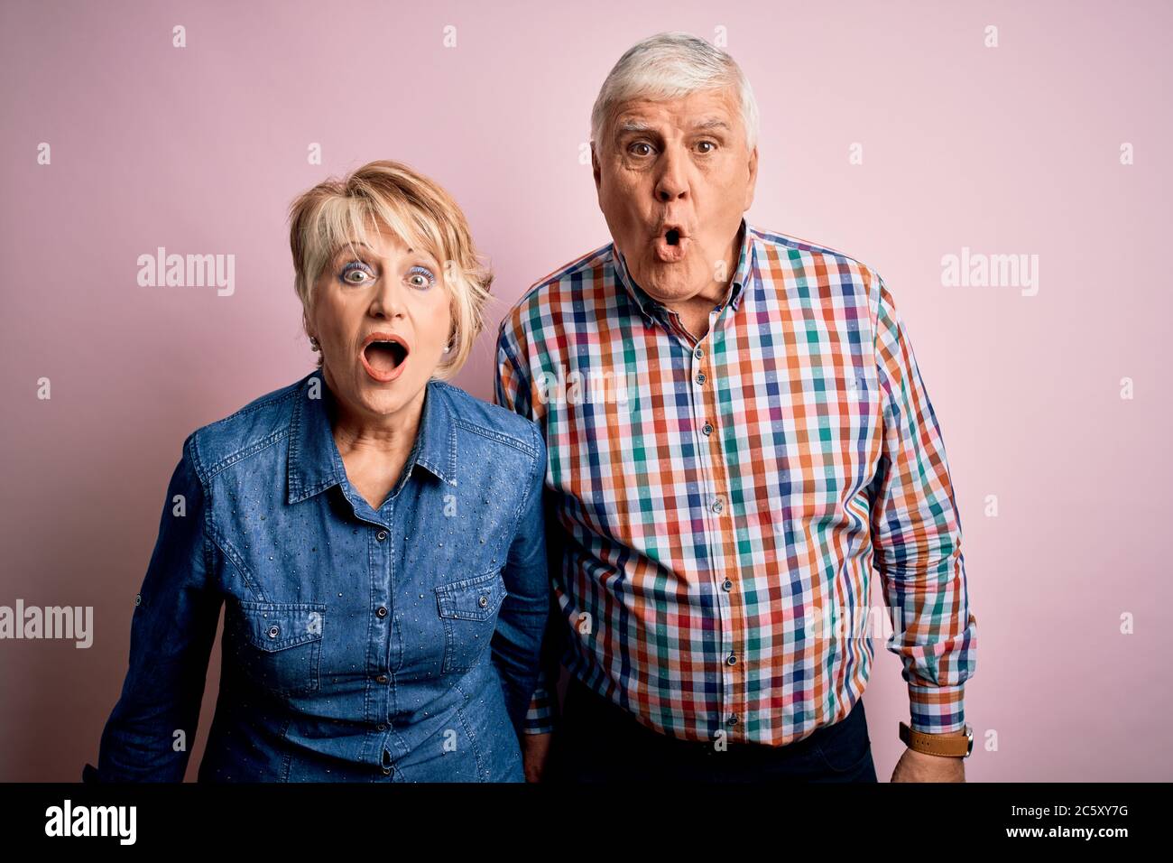 Senior beautiful couple standing together over isolated pink background ...