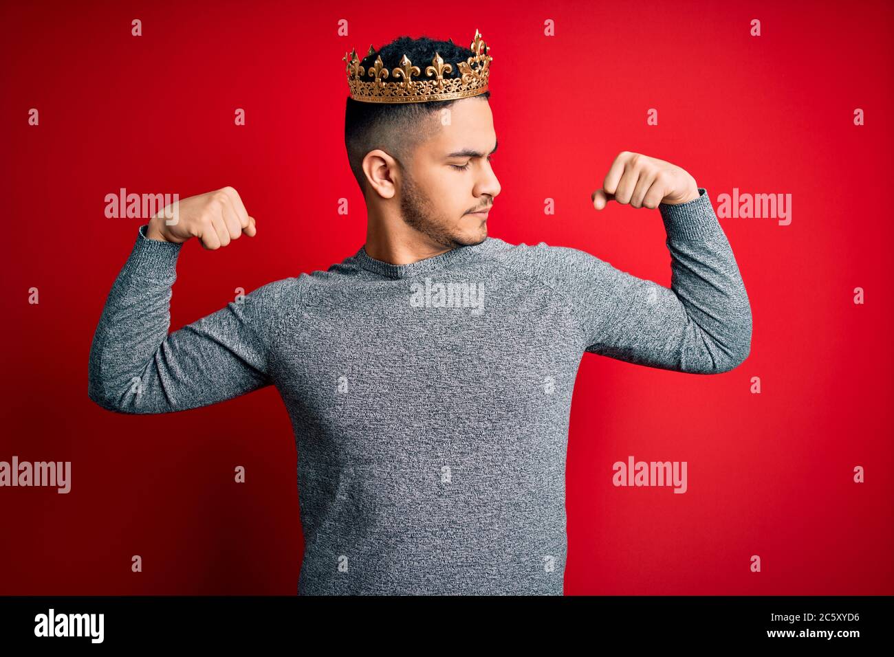Young handsome man wearing golden crown of prince over isolated red ...