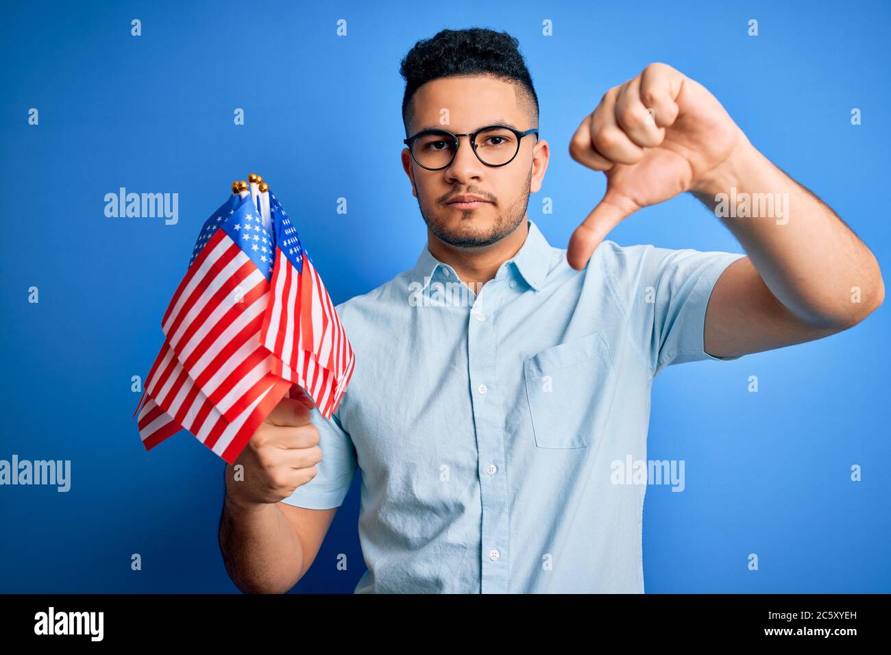 Young handsome patriotic man holding united states flags celebrating ...