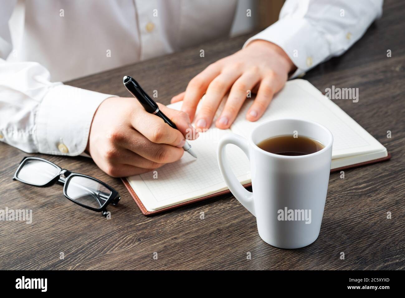 Man making notes with pen in notebook Stock Photo - Alamy
