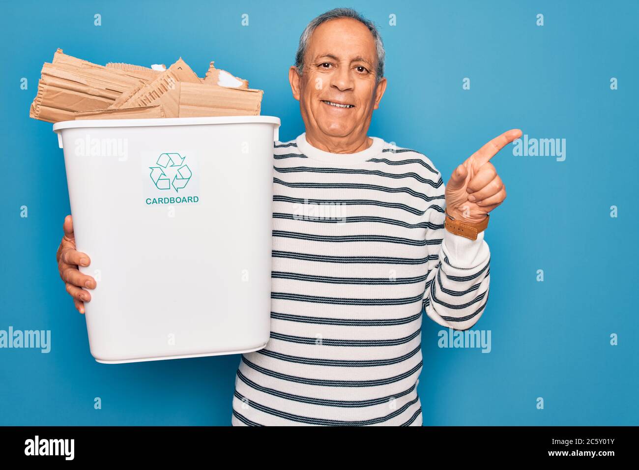 Senior man recycling holding trash can with cardboard to recycle over ...