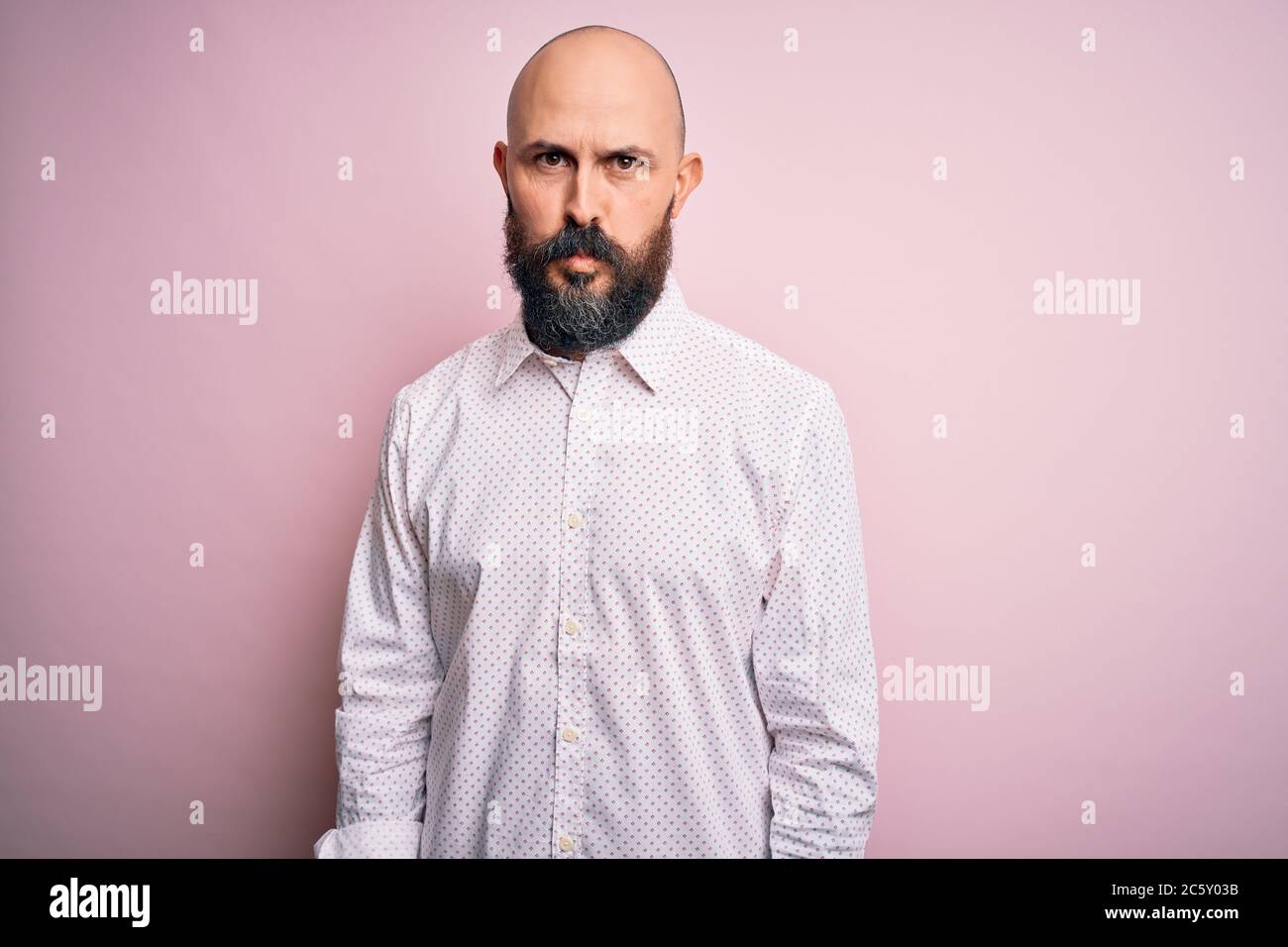 Handsome bald man with beard wearing elegant shirt over isolated pink ...