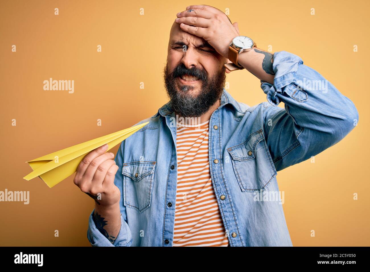 Handsome bald man with beard holding paper airplane over isolated ...