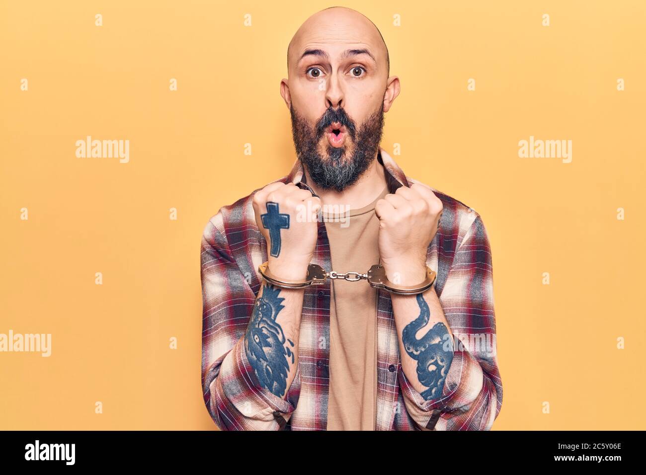Young handsome man wearing prisoner handcuffs scared and amazed with ...