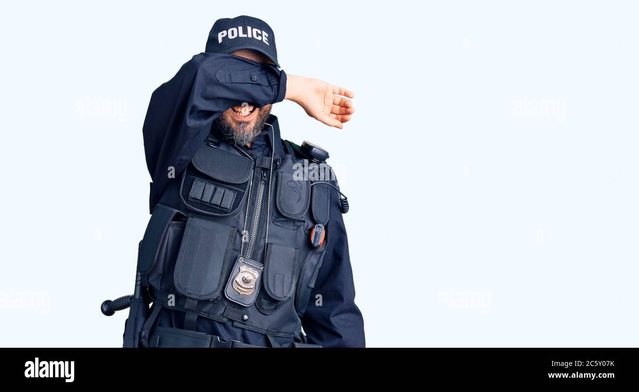 Young handsome man wearing police uniform covering eyes with arm ...