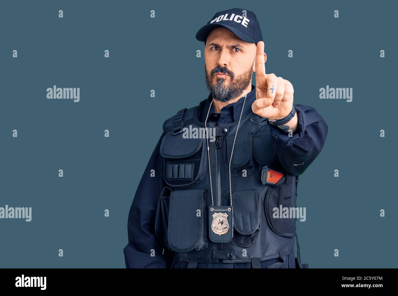 Young handsome man wearing police uniform pointing with finger up and ...