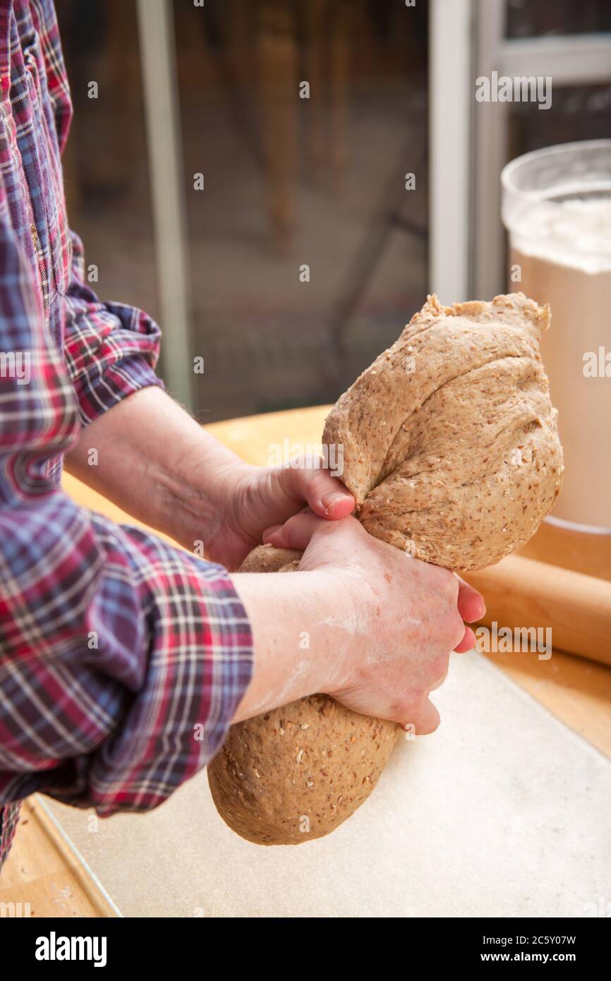Woman pinching off a section of multigrain bread dough into separate ...