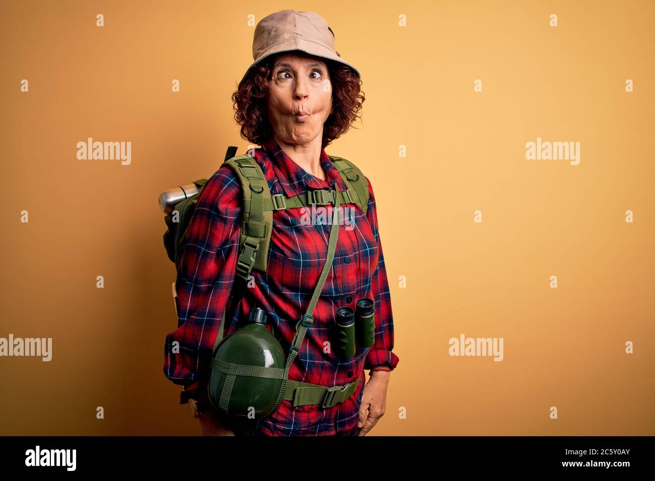 Middle age curly hair hiker woman hiking wearing backpack and water ...