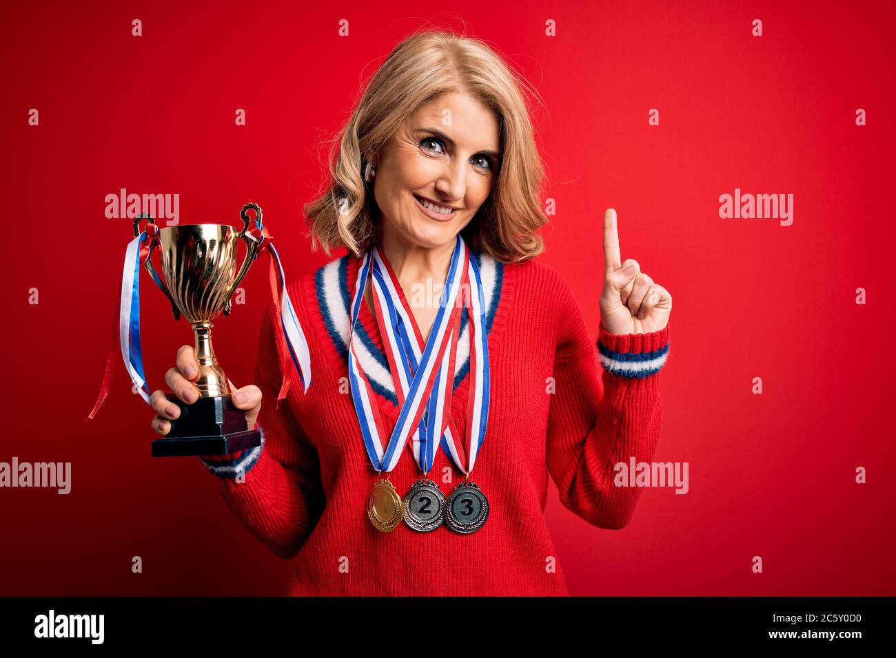 Middle age beautiful blonde successful woman wearing medals holding ...