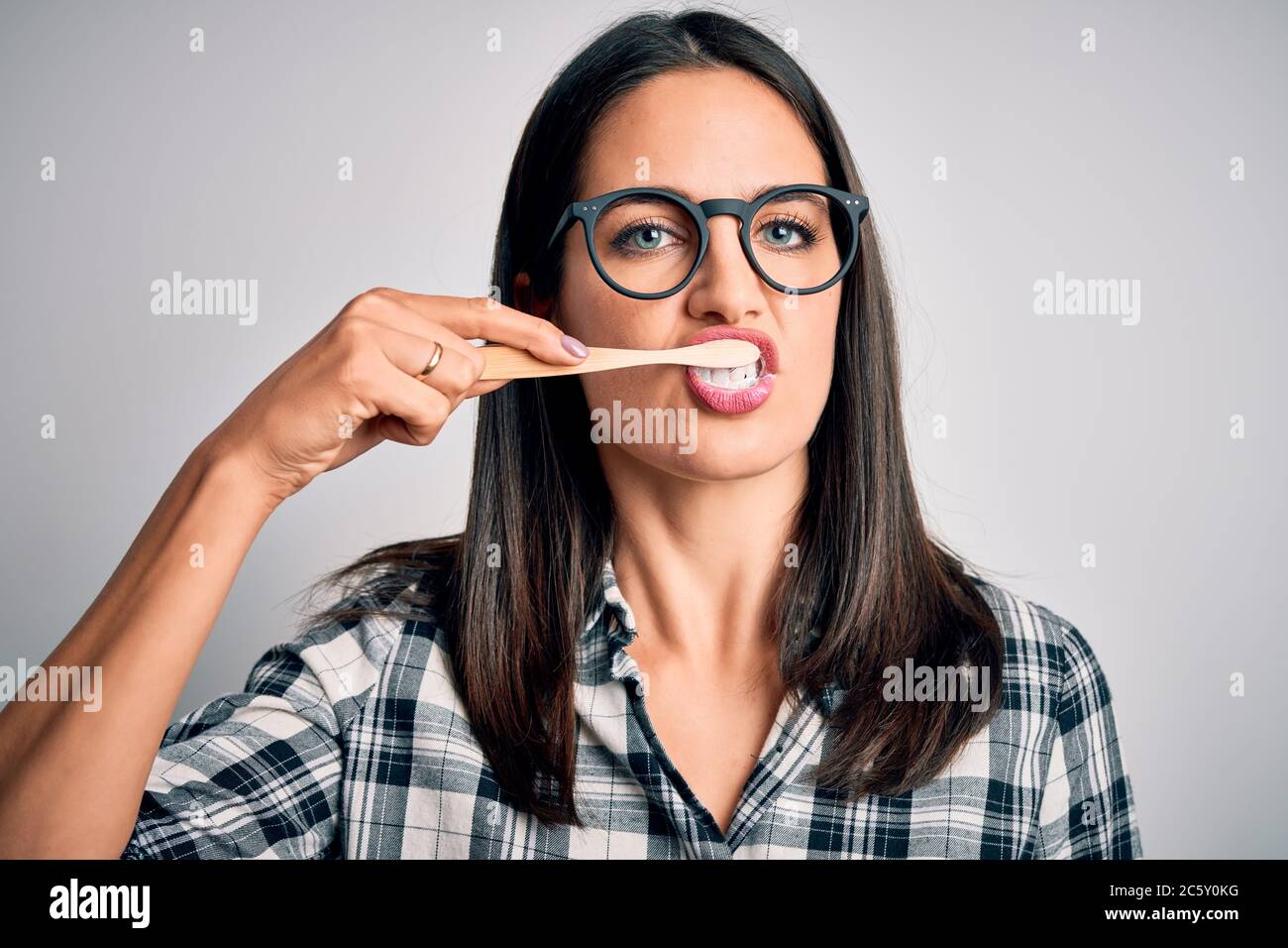Young caucasian woman wearing glasses brushing her teeth using tooth ...