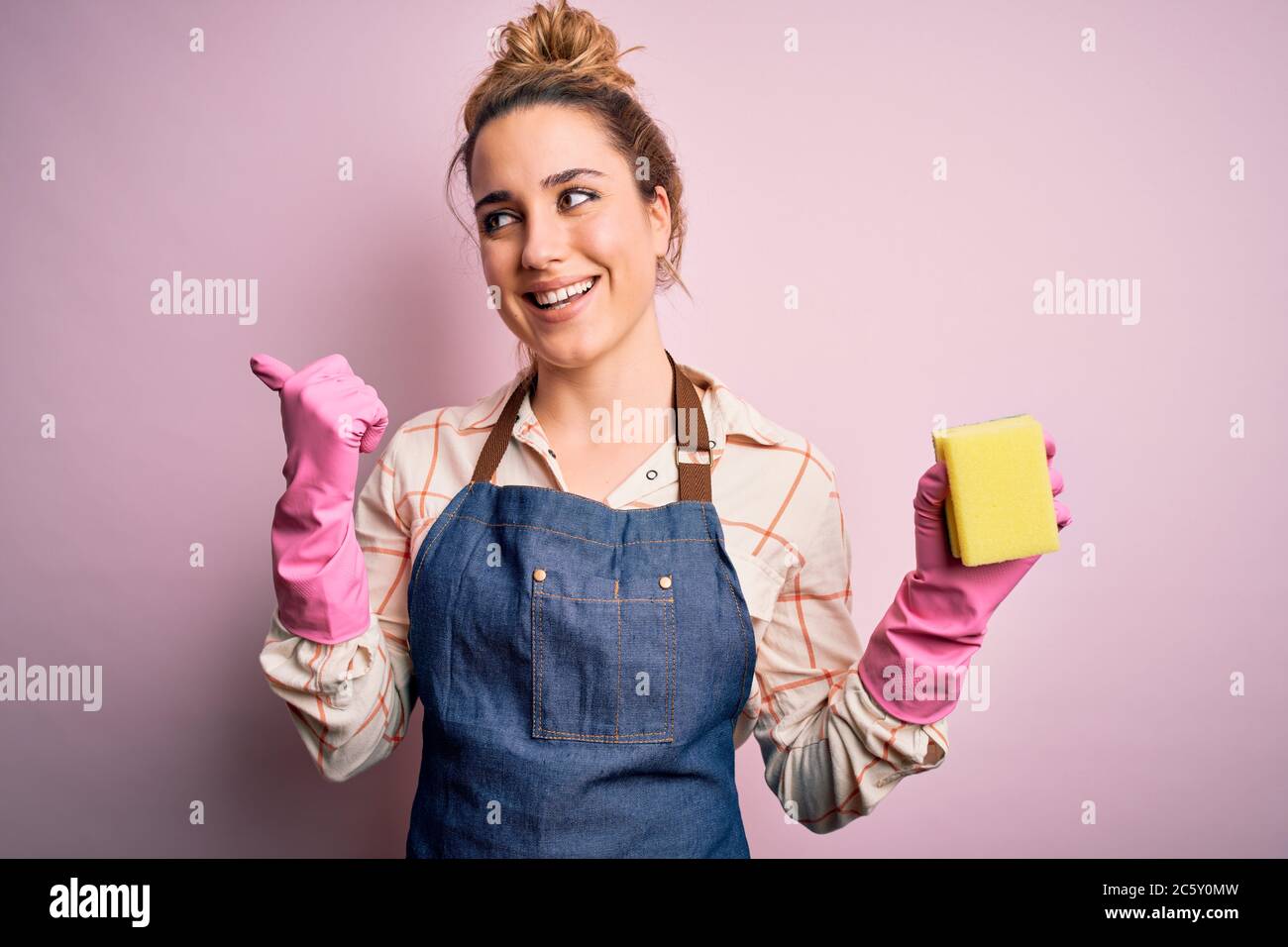 Beautiful blonde cleaner woman doing housework wearing arpon and gloves ...