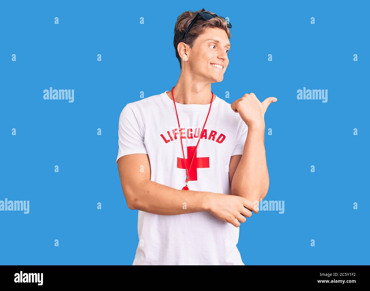 Young handsome man wearing lifeguard t shirt and whistle smiling with ...