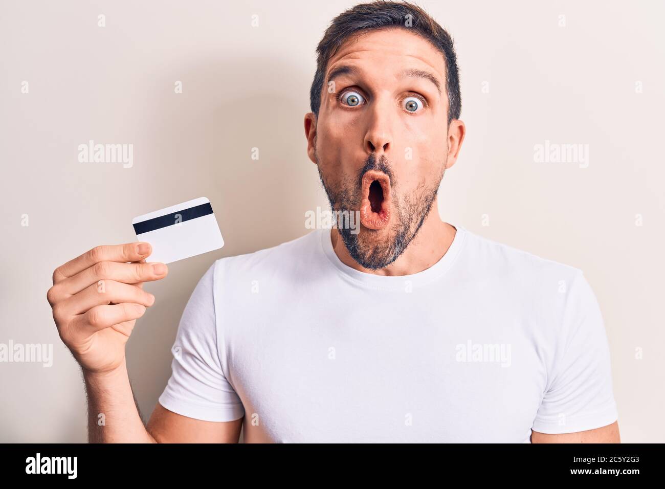 Young handsome customer man holding credit card over isolated white ...