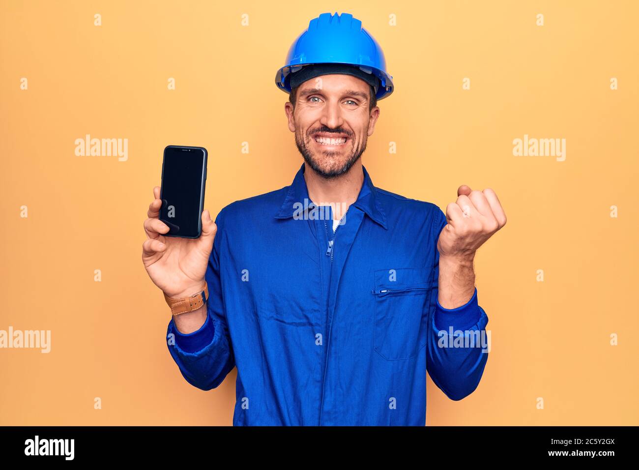 Young handsome worker man wearing uniform and hardhat holding ...