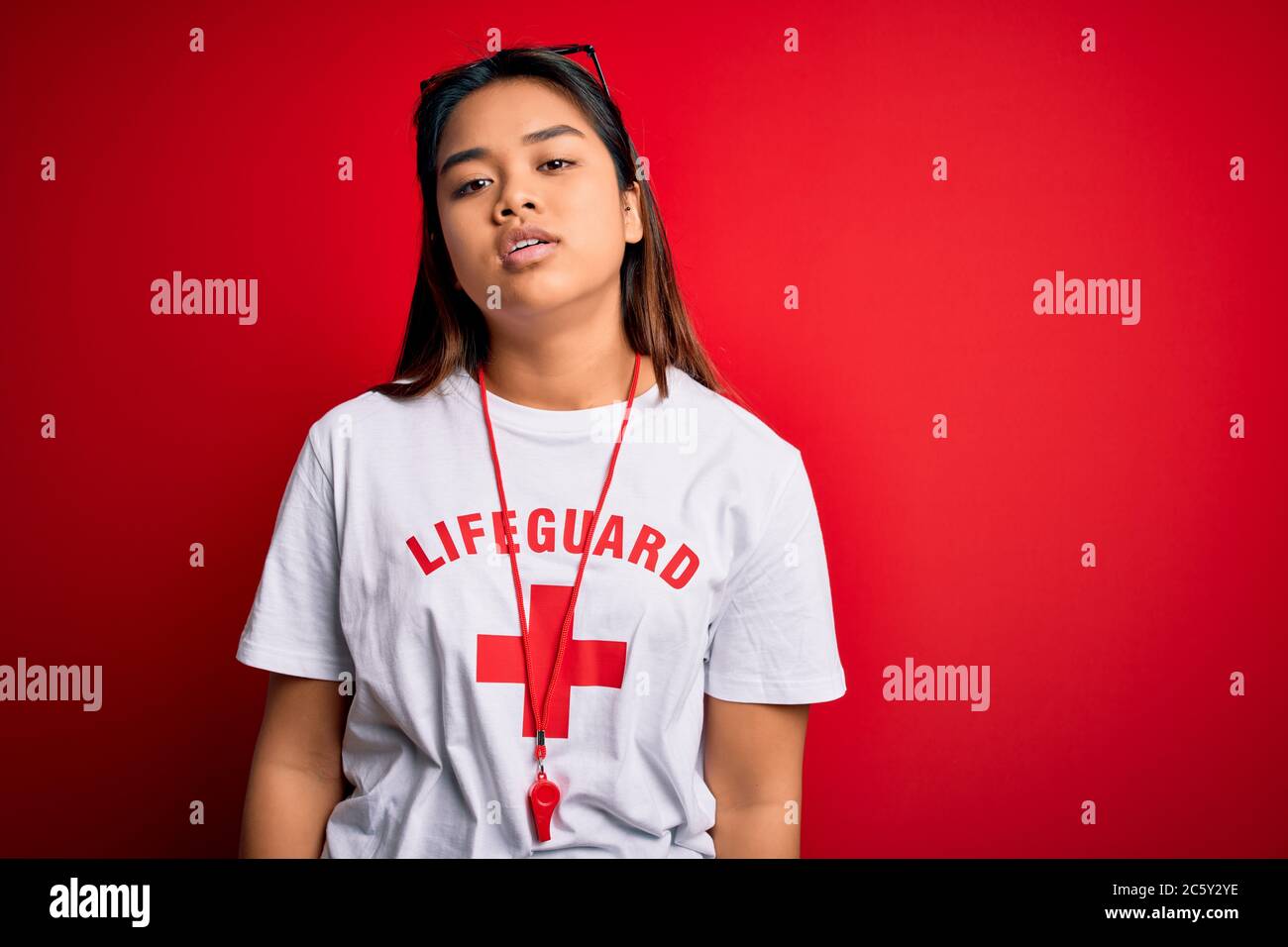 Young asian lifeguard girl wearing t-shirt with red cross using whistle ...