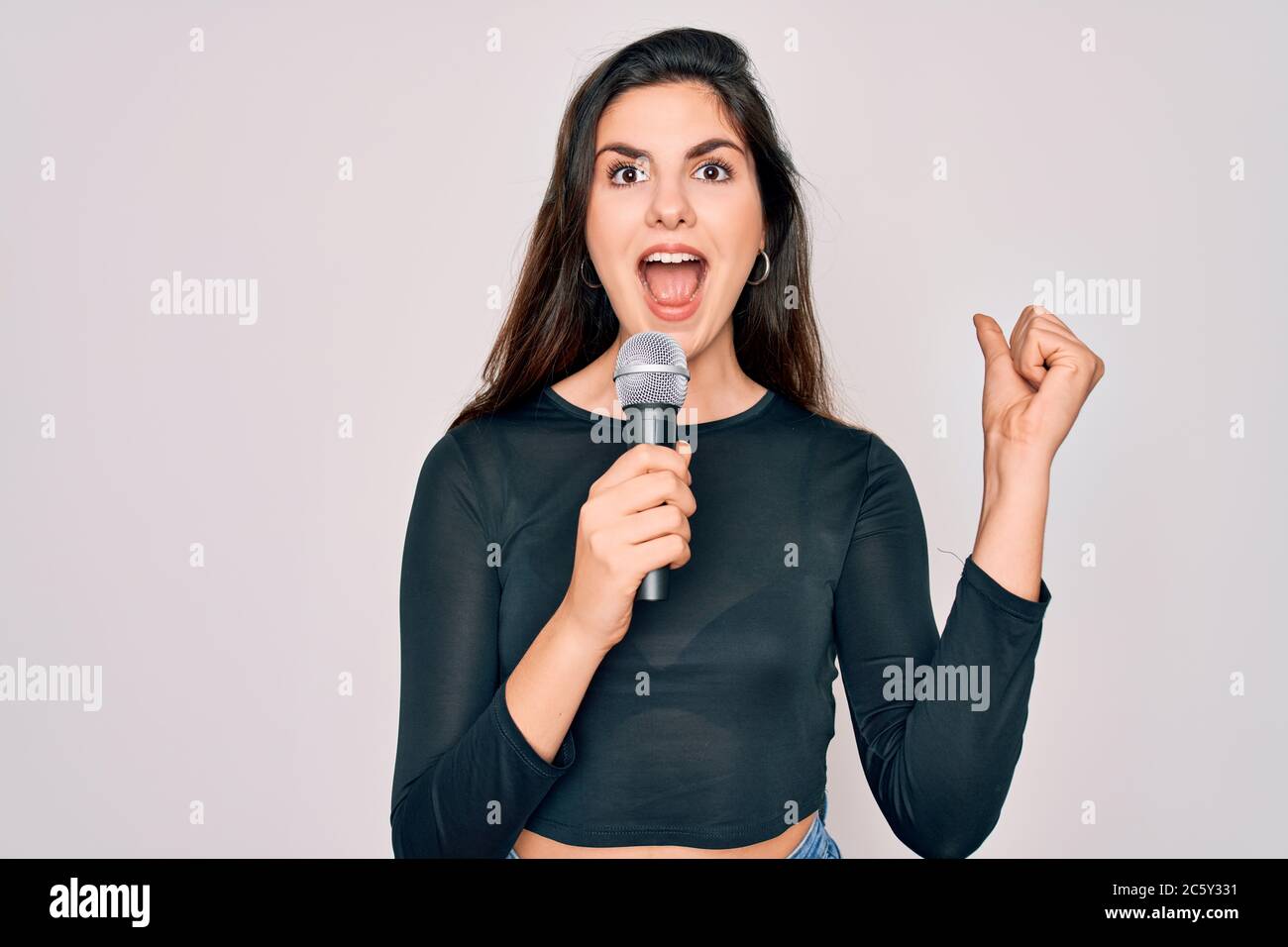 Young beautiful singer performer girl singing using music microphone ...