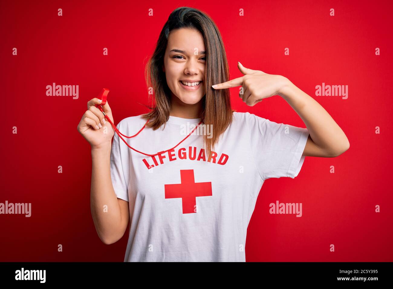 Young beautiful brunette lifeguard girl wearing t-shirt with red cross ...