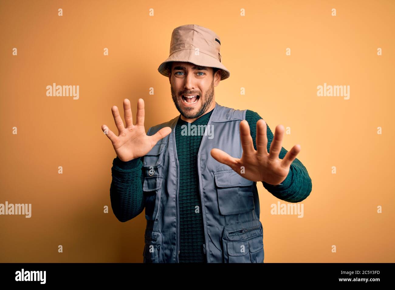 Handsome tourist man with beard on vacation wearing explorer hat over ...