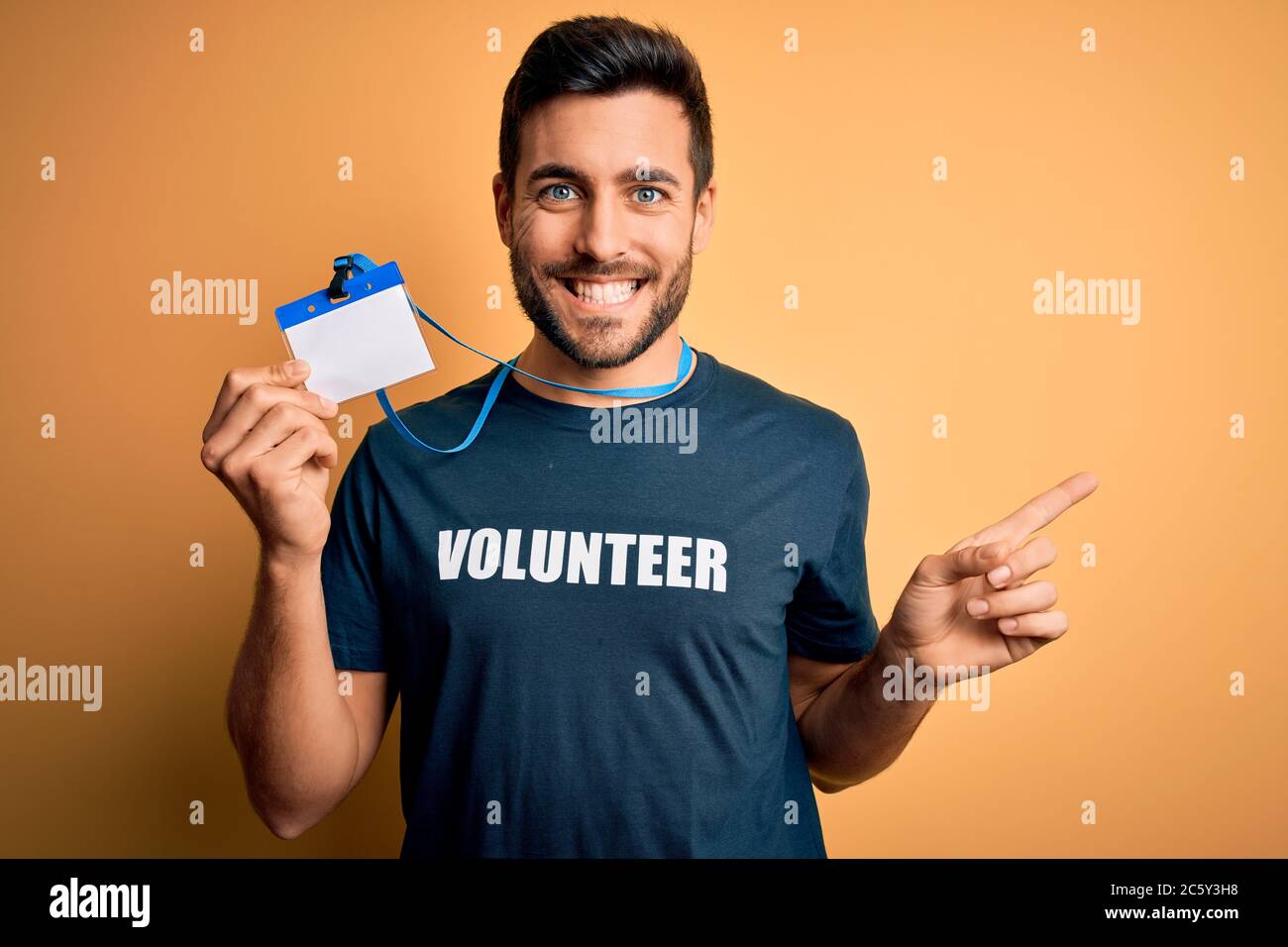 Handsome volunteer man with beard holding id card identification over ...