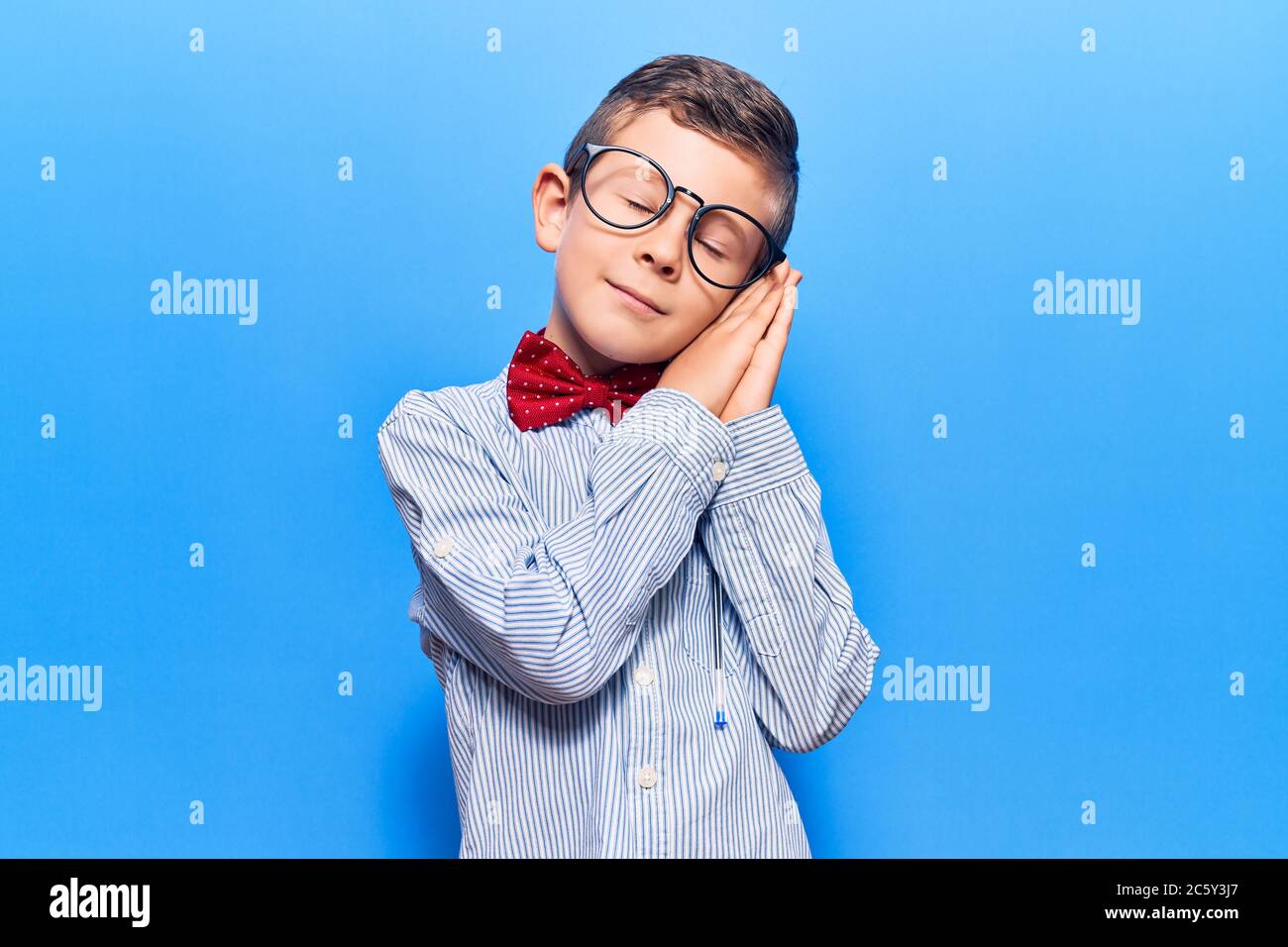 Cute blond kid wearing nerd bow tie and glasses sleeping tired dreaming ...