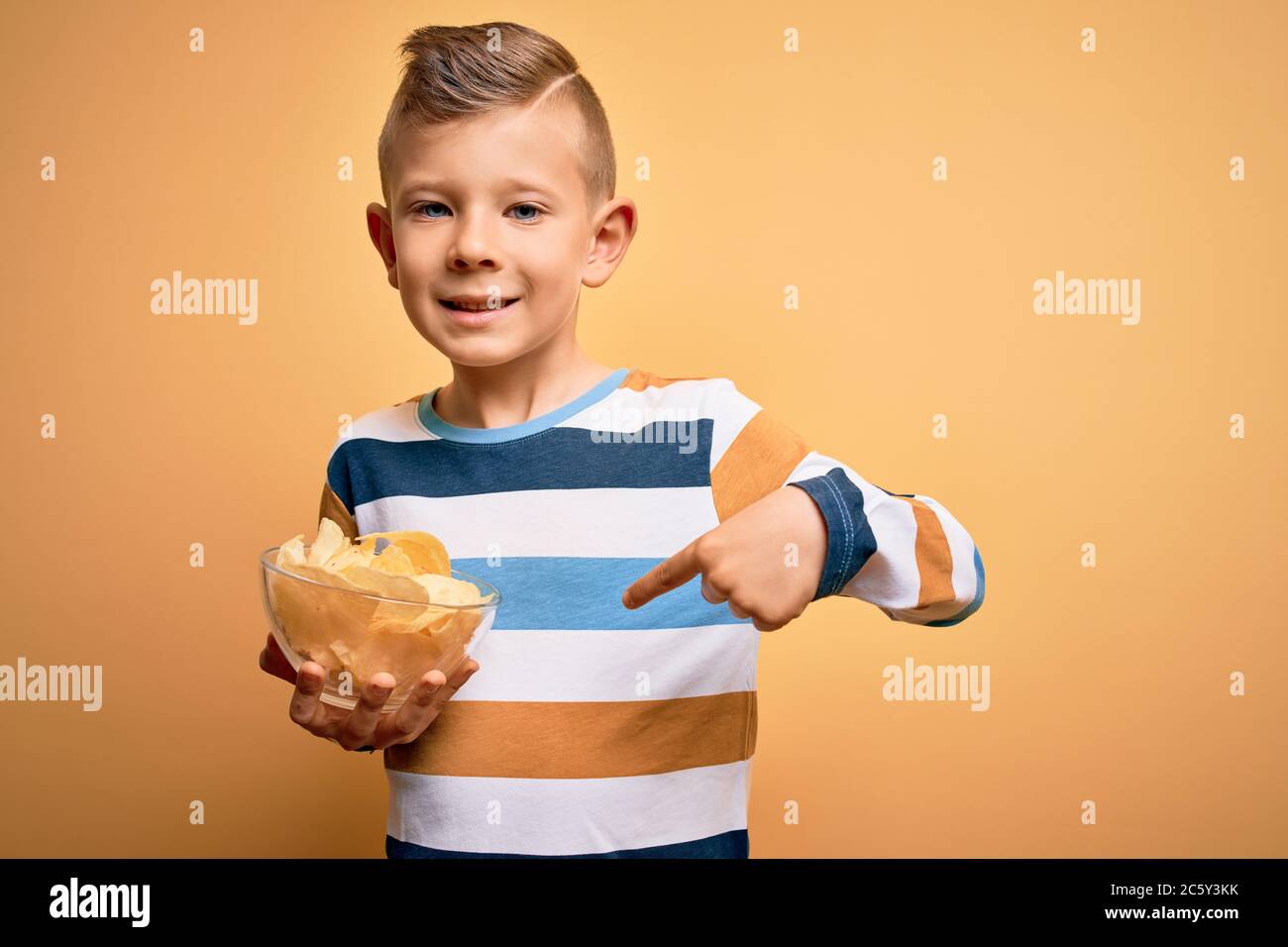 Young little caucasian kid eating unheatlhy potatoes crisps chips over ...