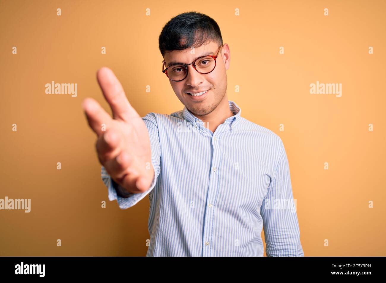 Young handsome hispanic business man wearing nerd glasses over yellow ...