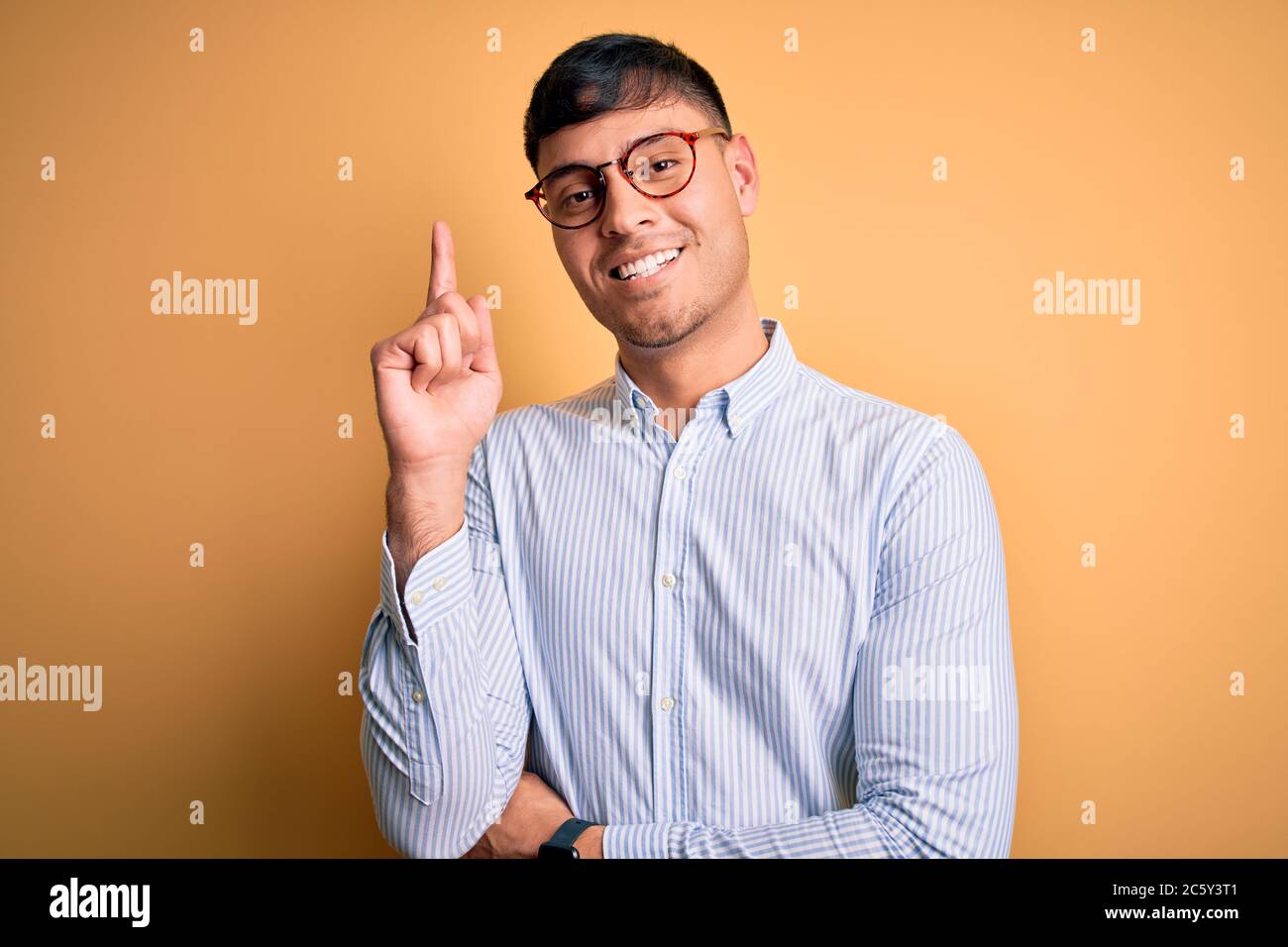 Young handsome hispanic business man wearing nerd glasses over yellow ...