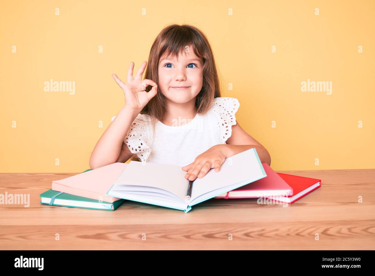 Little caucasian kid girl with long hair studying for school exam doing ...