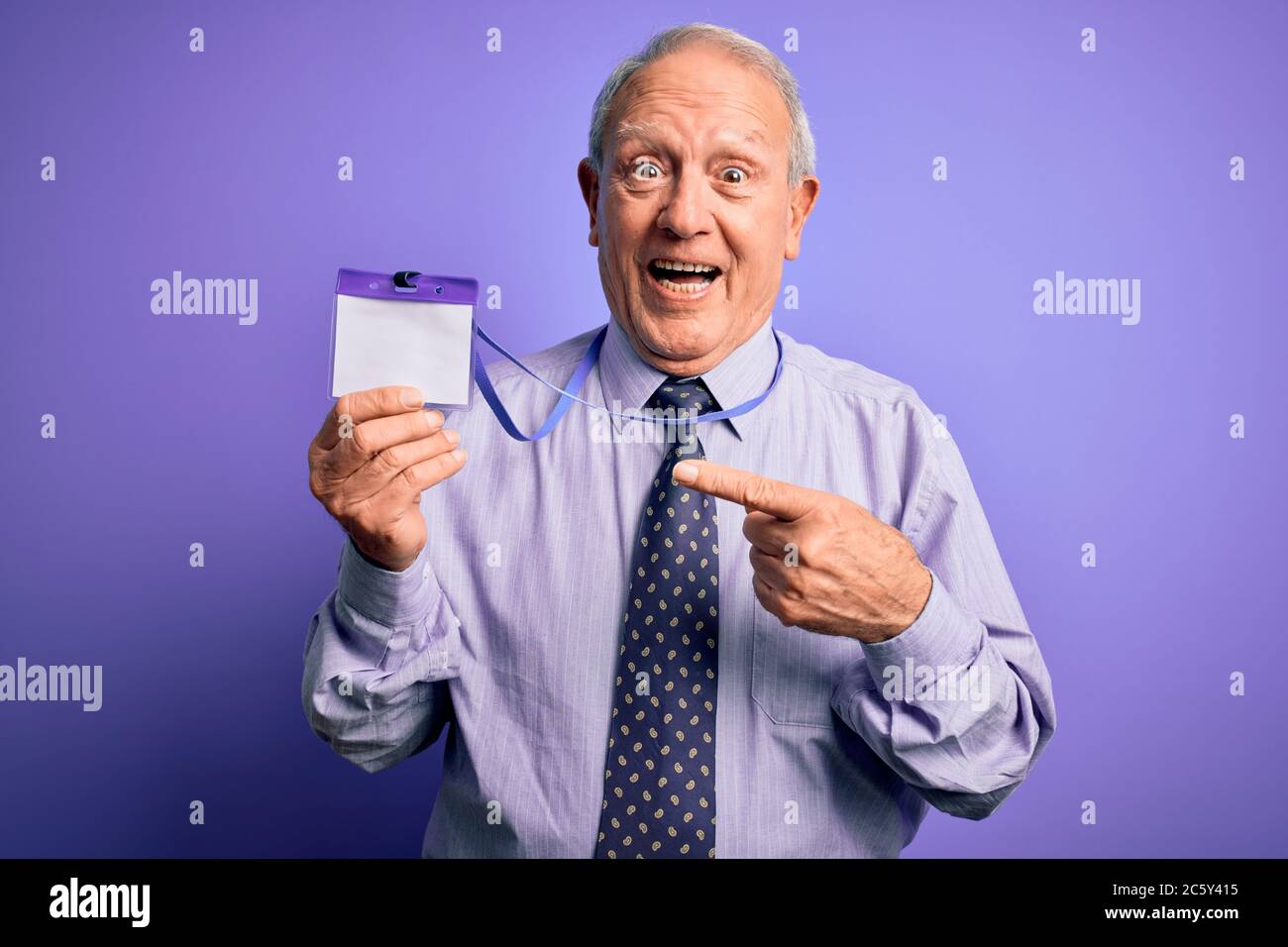 Senior grey haired business man holding identification tag over purple ...