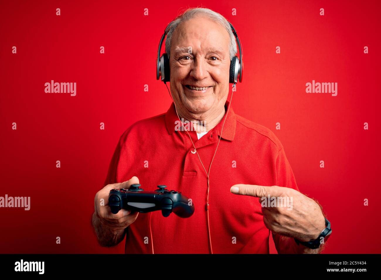 Senior grey haired gamer man playing video games using gamepad joystick ...