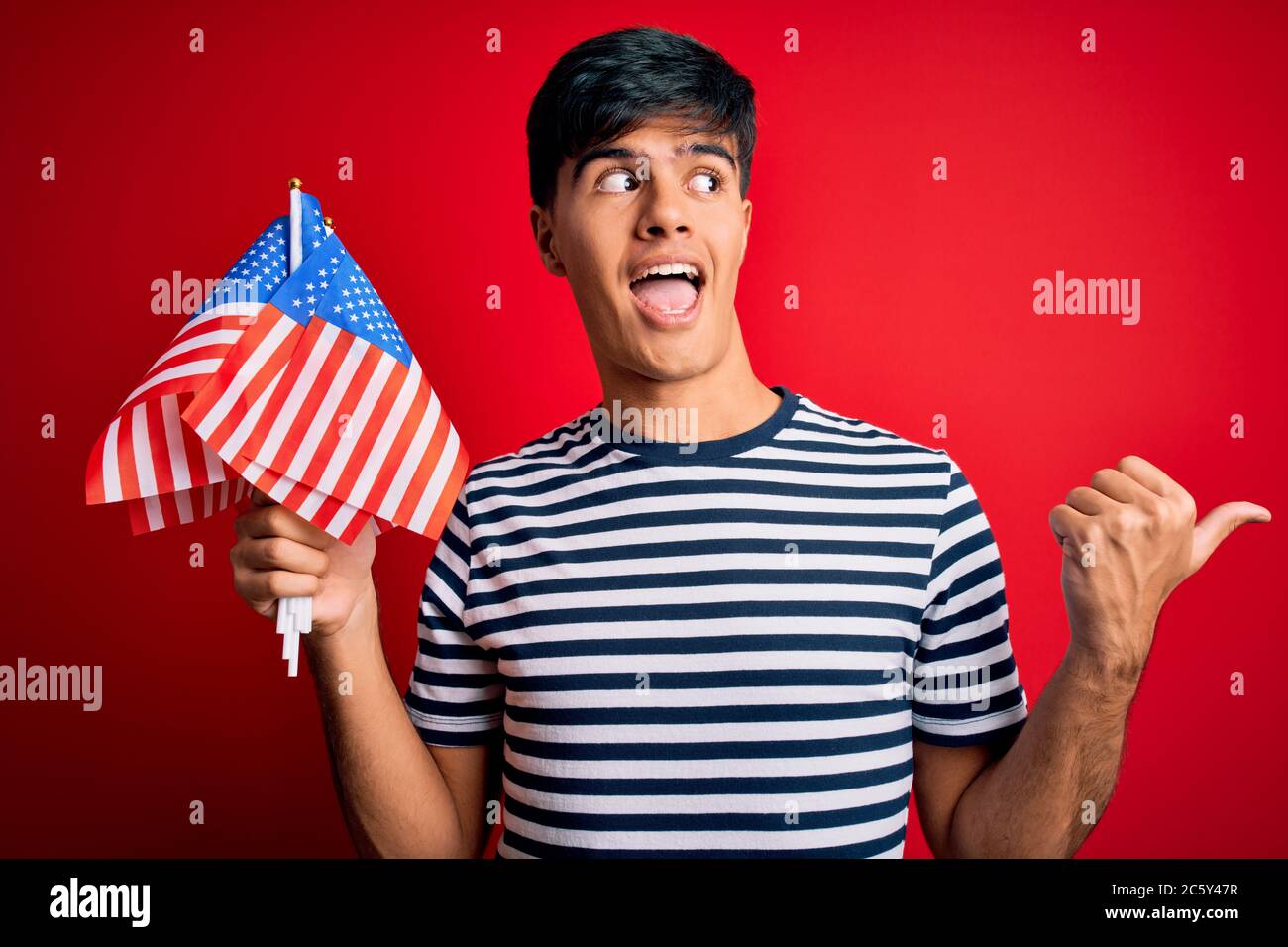 Young handsome patriotic man holding united states flags celebrating ...