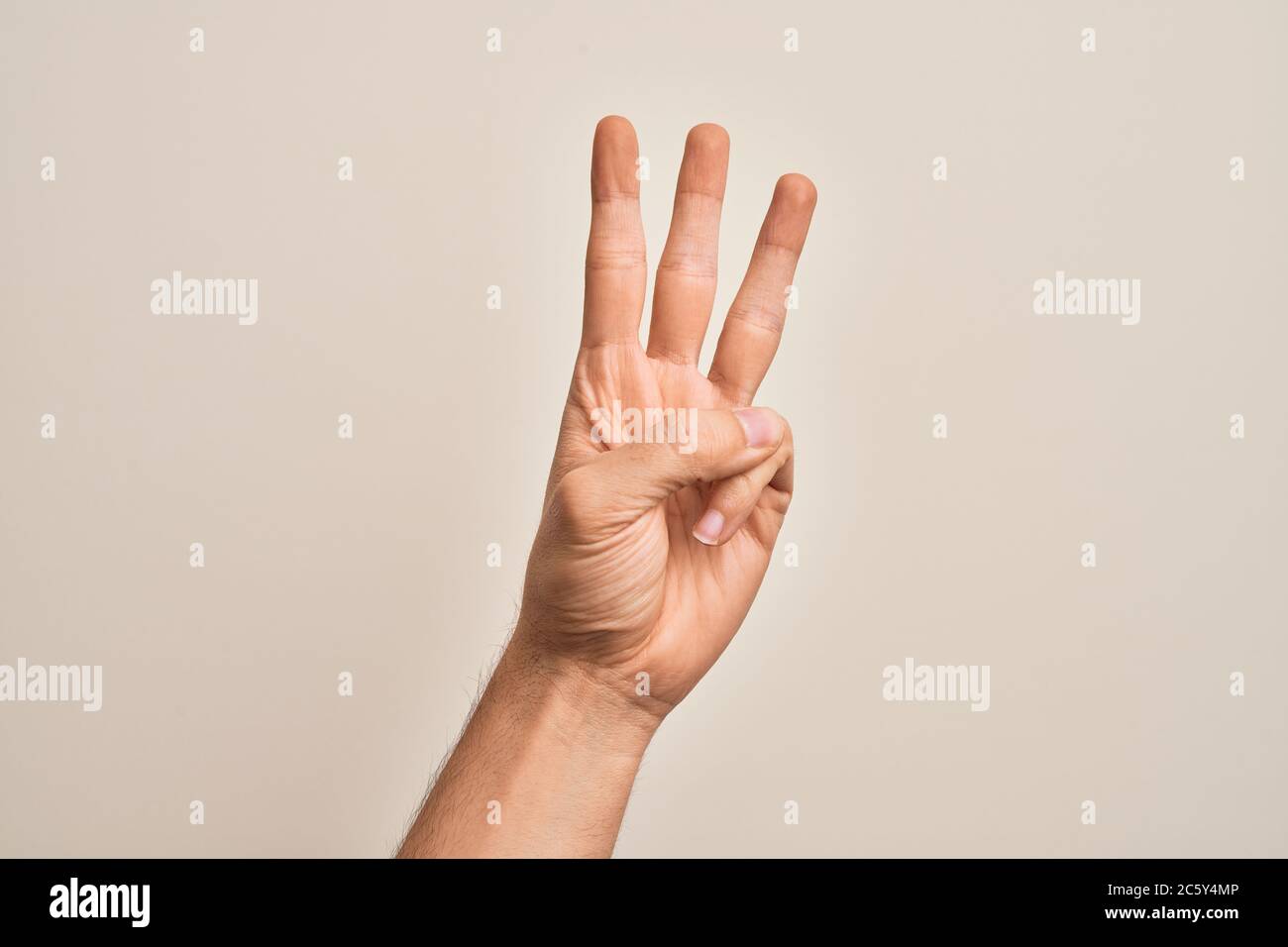 Hand of caucasian young man showing fingers over isolated white background counting number 3 ...