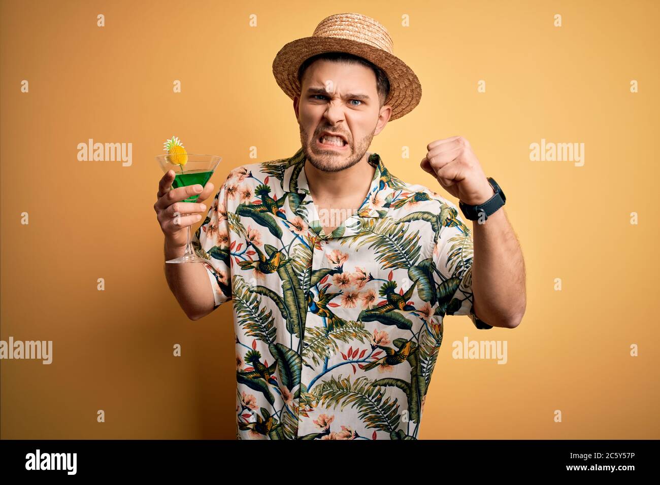 Young man on vacation wearing summer hat drinking a party cocktail over ...