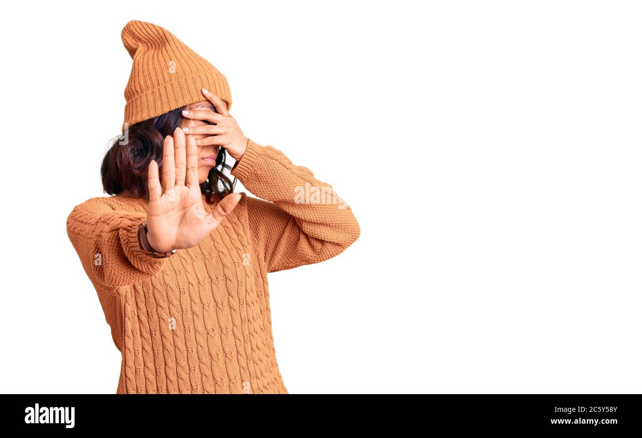 Young beautiful mixed race woman wearing wool sweater and winter hat ...