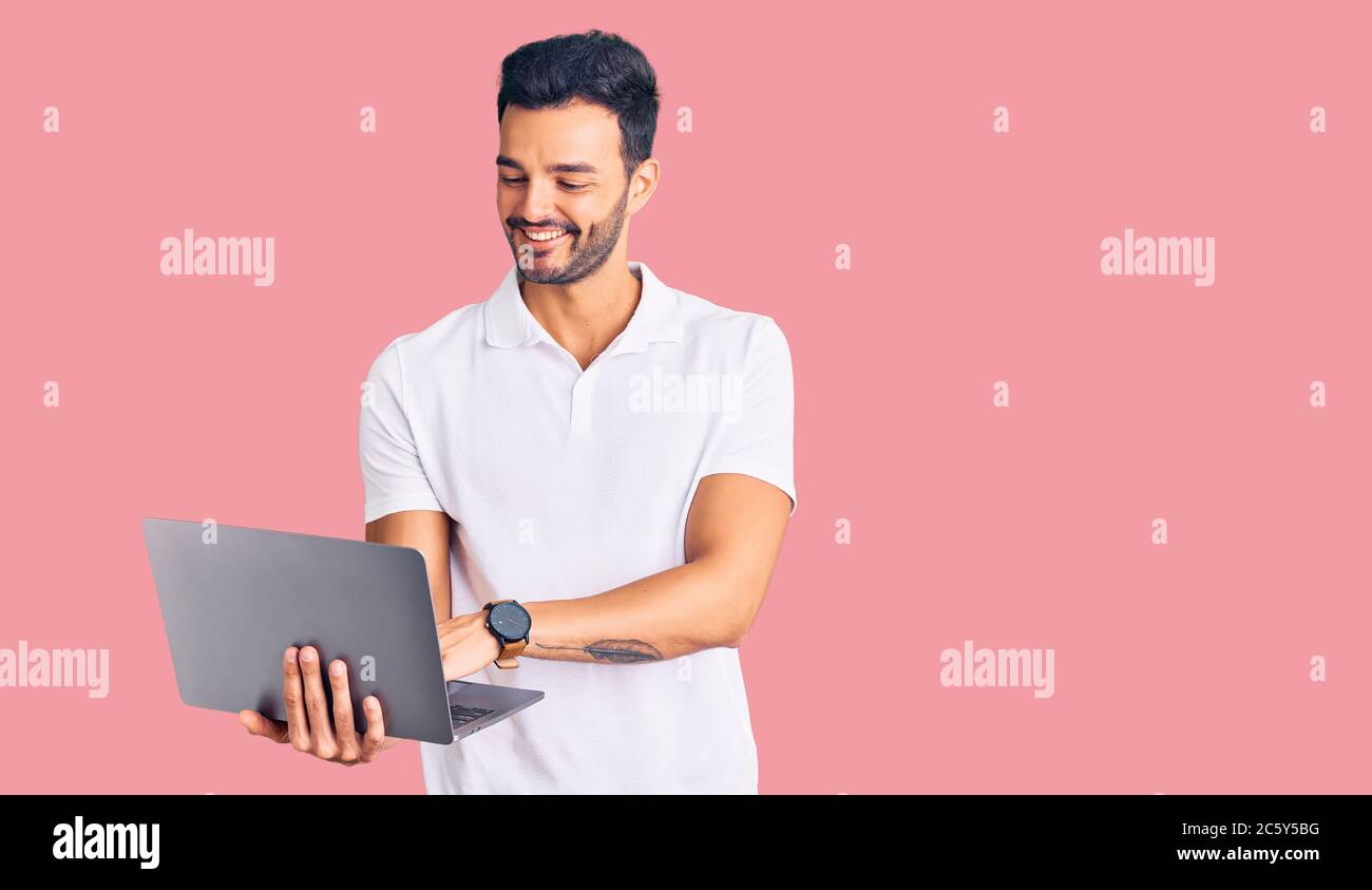 Young handsome hispanic man working using computer laptop looking ...