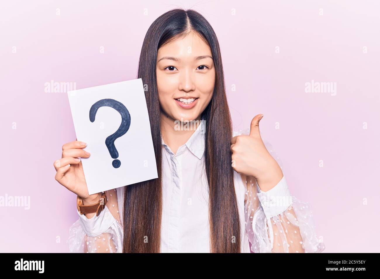 Young beautiful chinese woman holding question mark smiling happy and ...