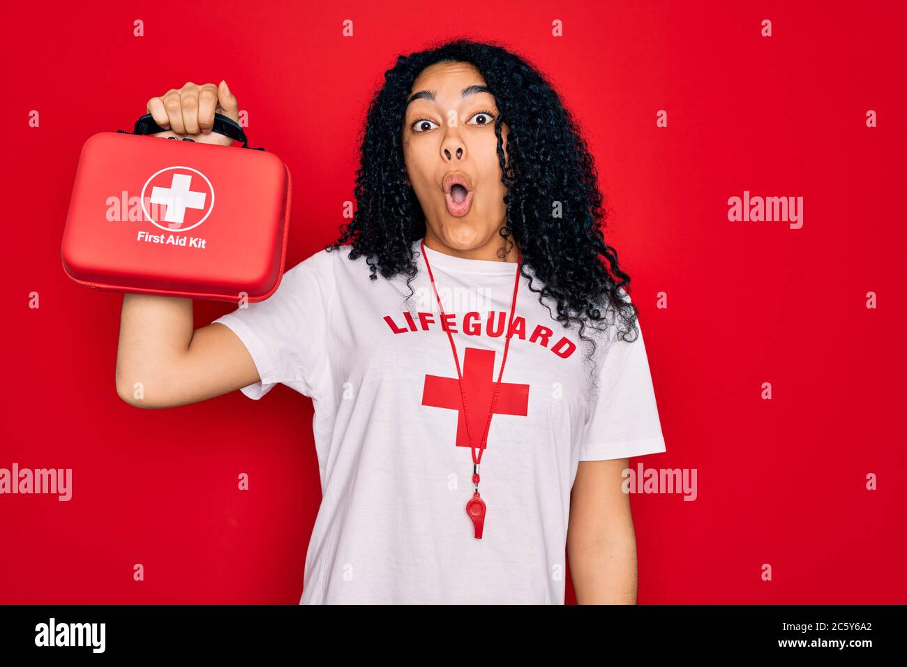 Young african american curly lifeguard woman wearing whistle holding ...