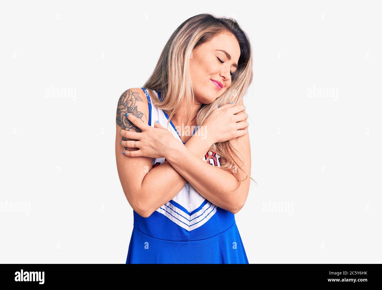 Young beautiful blonde woman wearing cheerleader uniform hugging ...