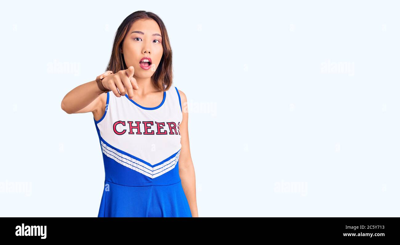 Young beautiful chinese girl wearing cheerleader uniform pointing ...