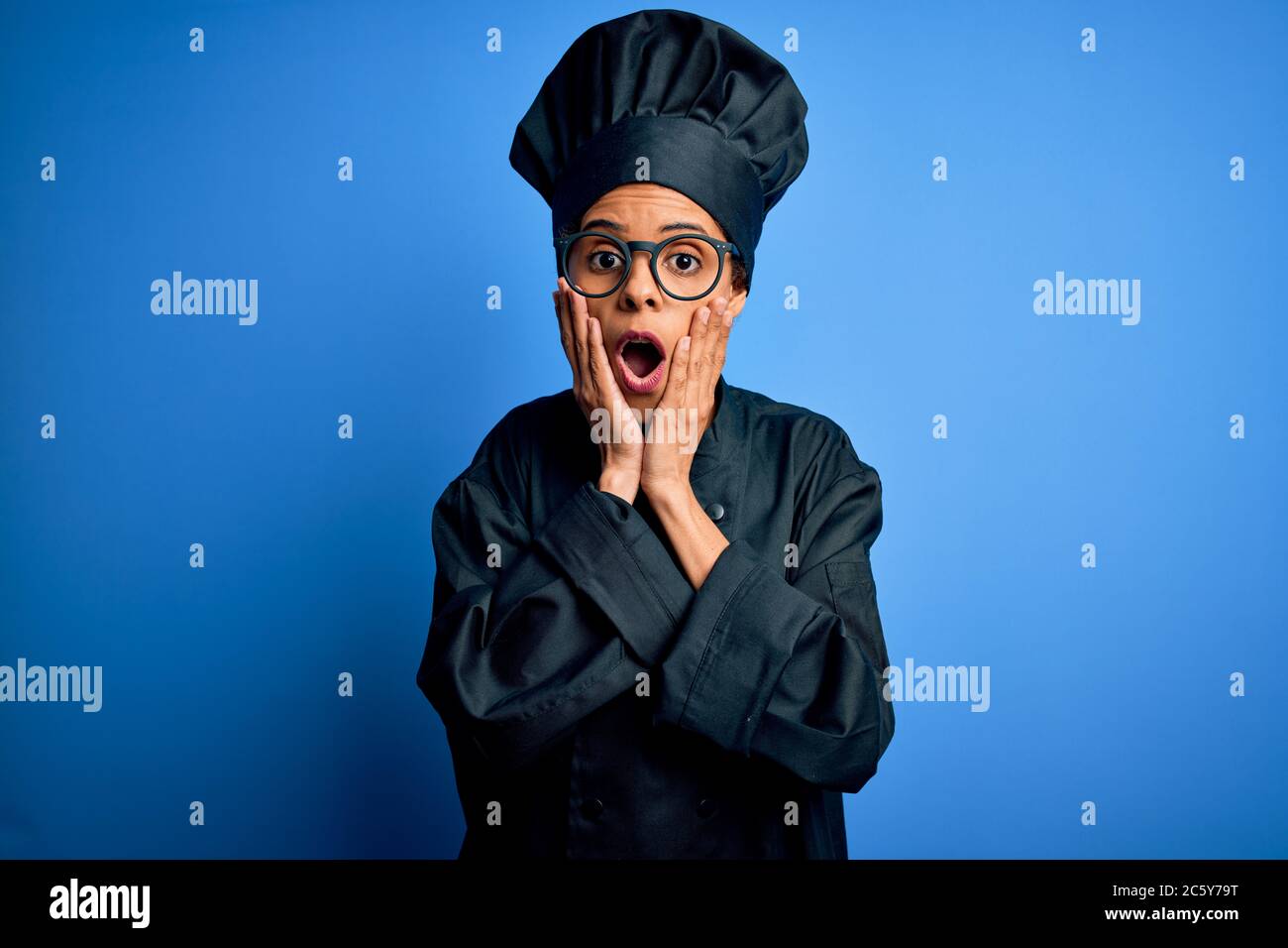Young african american chef woman wearing cooker uniform and hat over ...