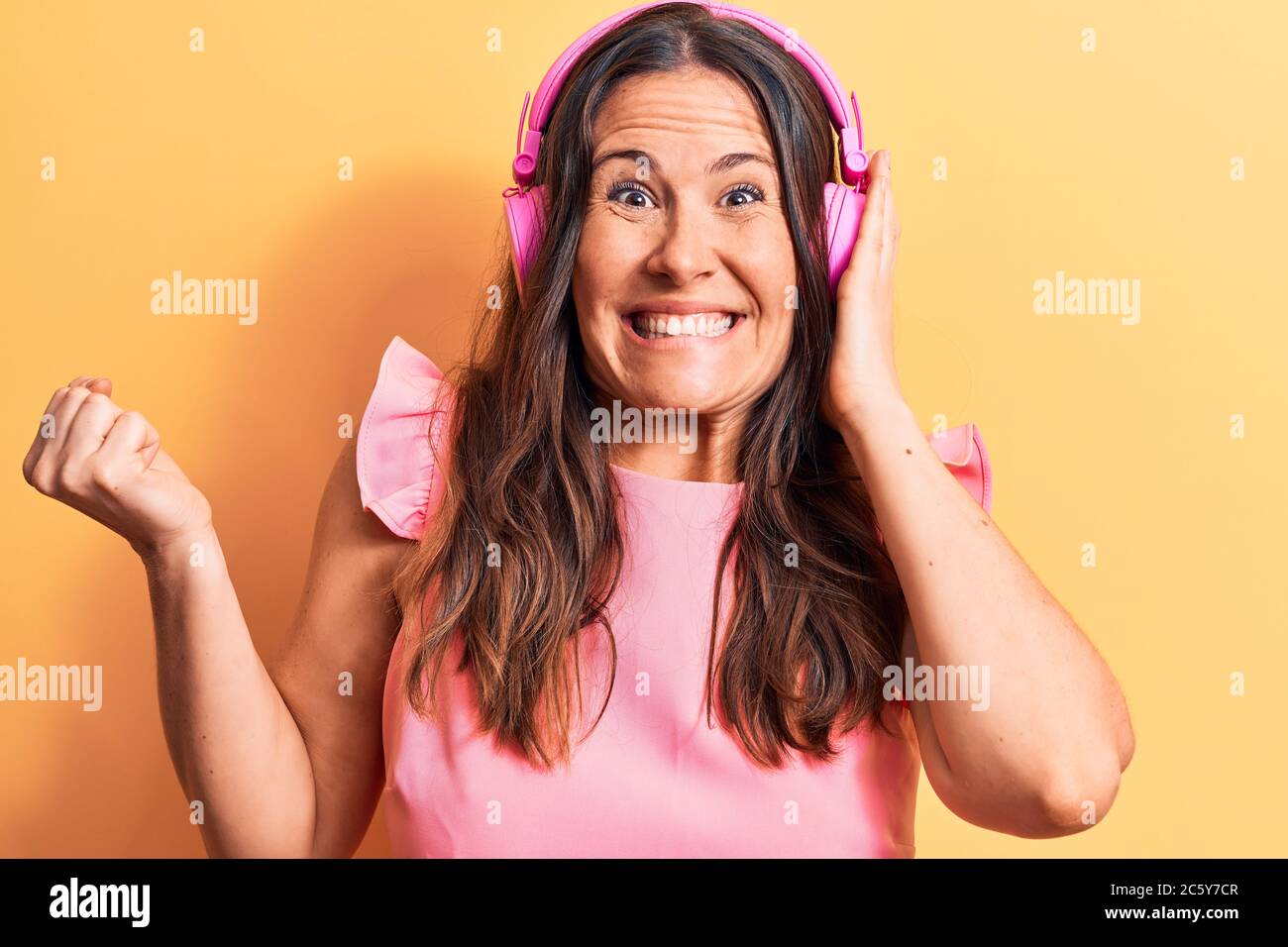 Young beautiful brunette woman listening to music using headphones over ...