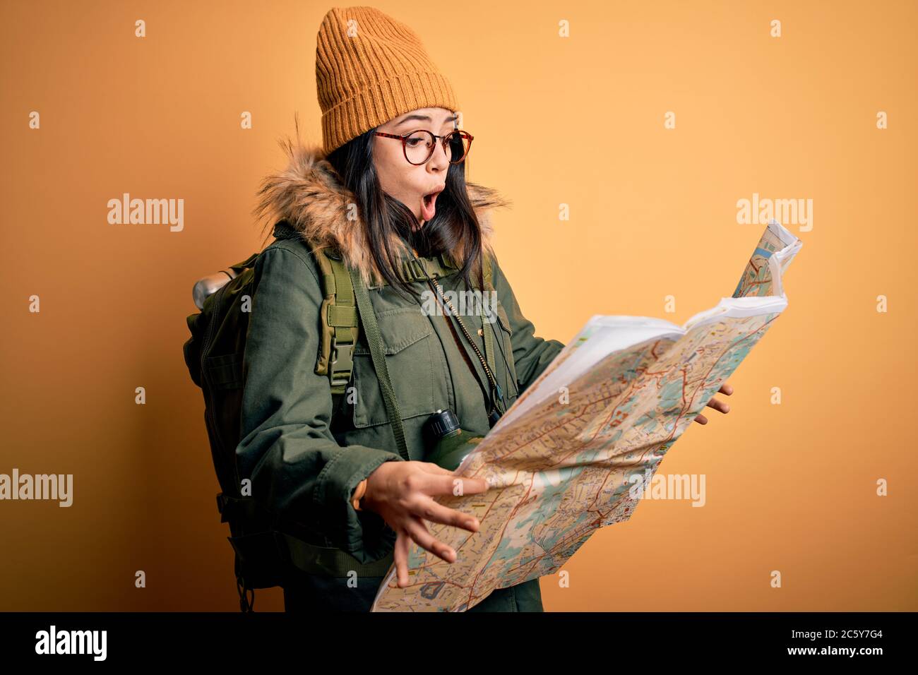 Young hiker woman wearing hiking backpack looking at tourist map over ...