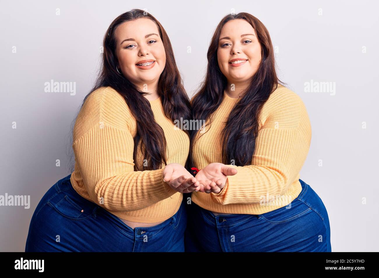 Young plus size twins wearing casual clothes smiling with hands palms ...