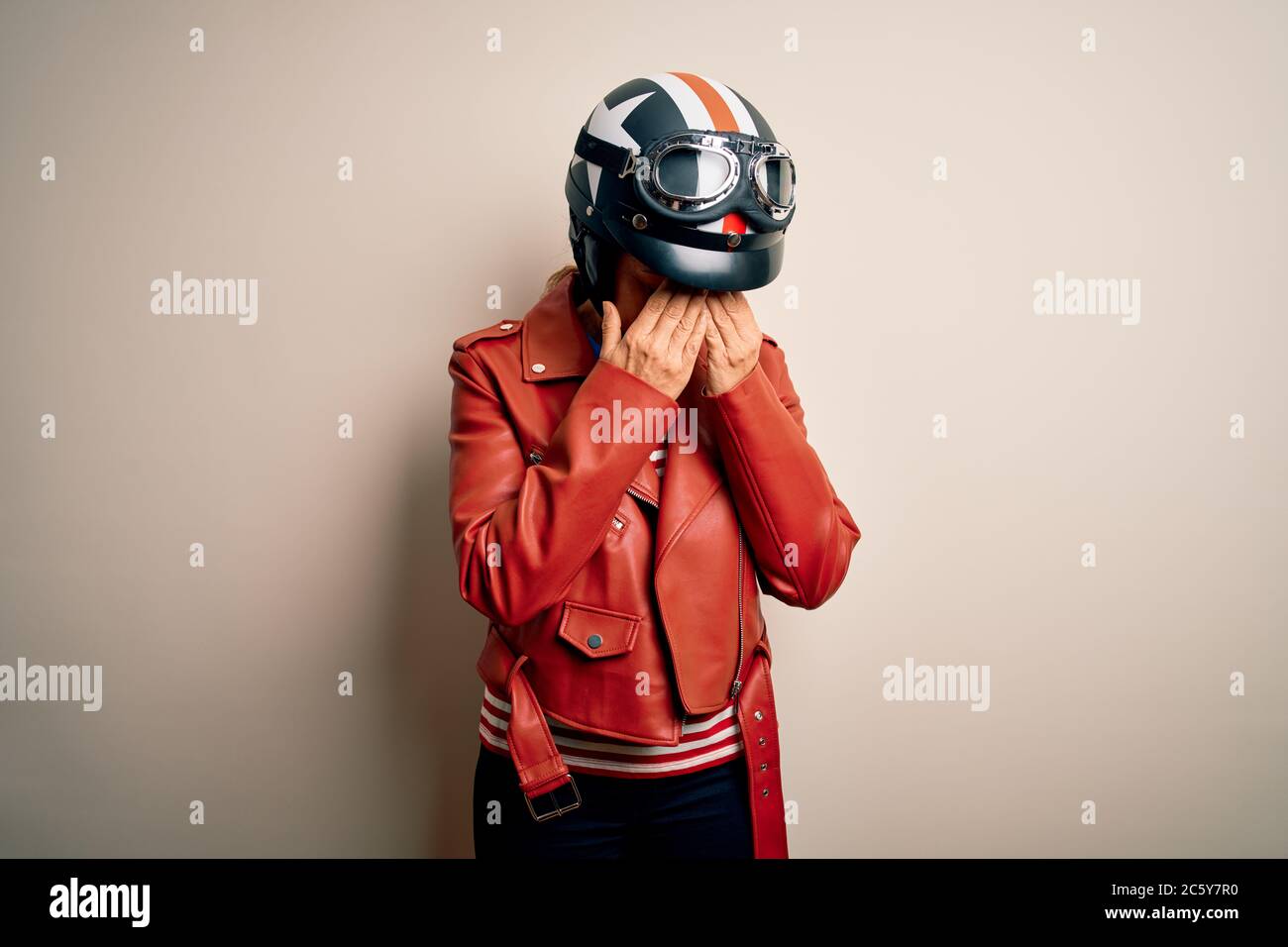 Middle age motorcyclist woman wearing motorcycle helmet and jacket over ...