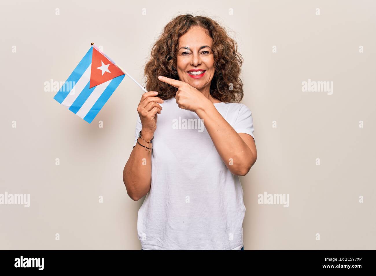 Middle age beautiful tourist woman holding cuban flag over isolated ...